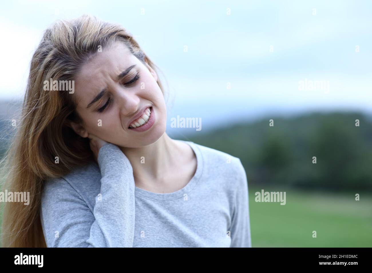 Teen complaining suffering neck ache in a field Stock Photo - Alamy