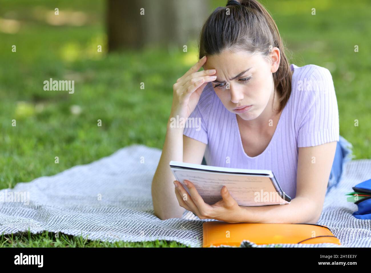 Worried student studying reading notes lying in a campus or park Stock ...