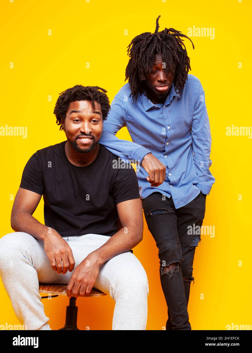 two african american guys posing cheerful together on yellow background ...