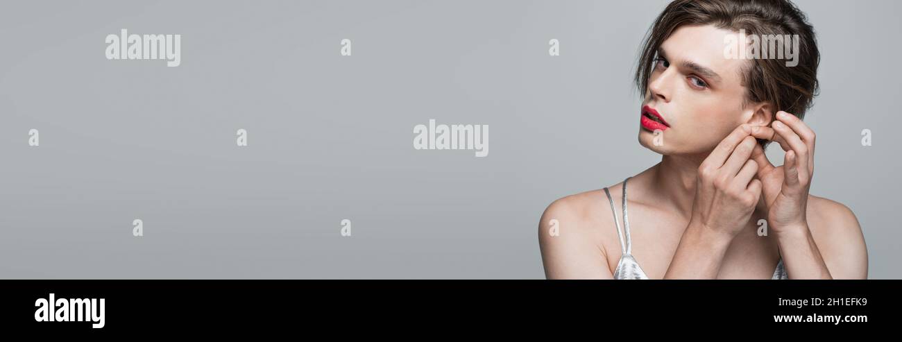 young transgender man touching ear isolated on grey, banner Stock Photo ...