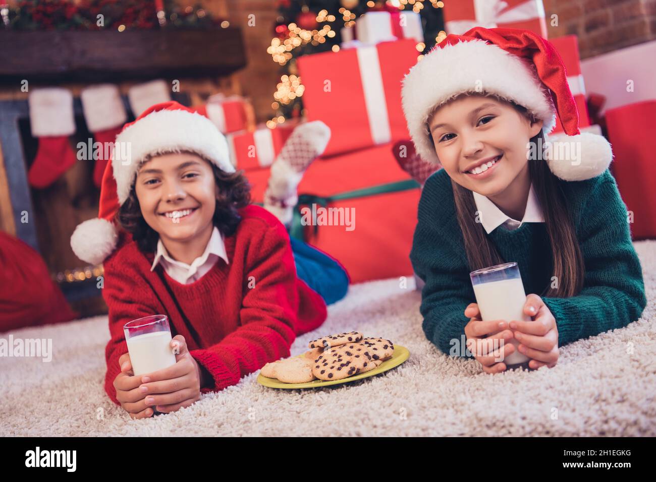 Portrait of attractive cheerful siblings lying on floor drinking milk ...