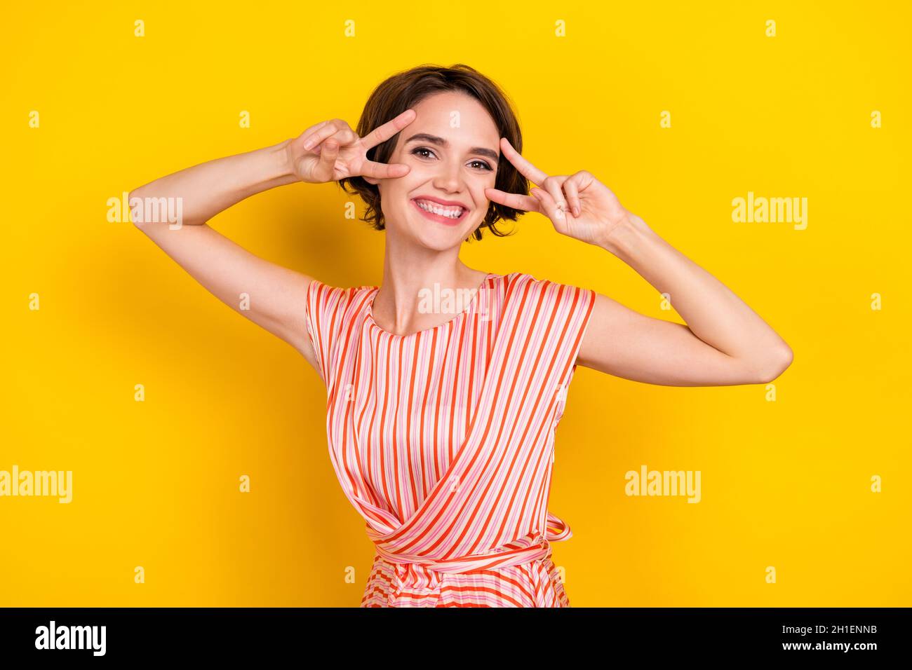 Portrait of attractive cheerful girl showing double v-sign near eye ...