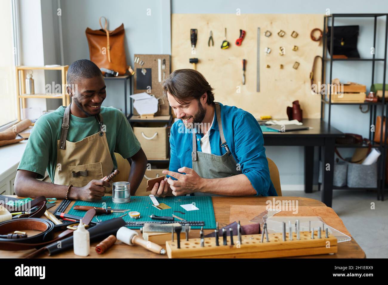 Portrait of smiling male artisan teaching young apprentice in ...