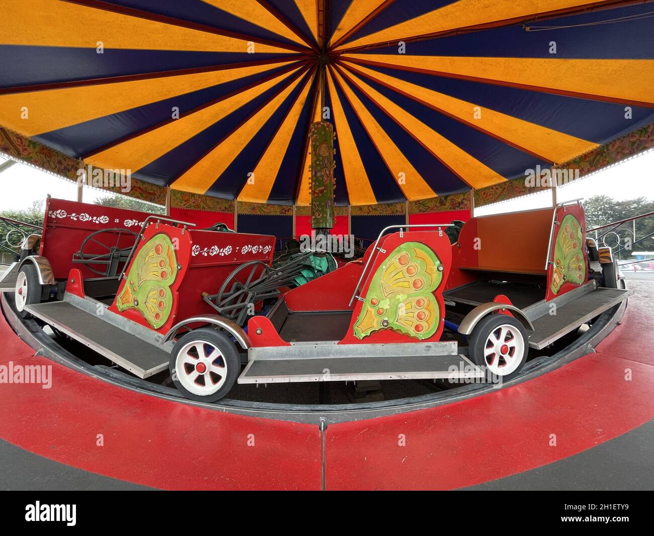 Closeup shot of amusement rides for kids with red cars in the fun fai ...