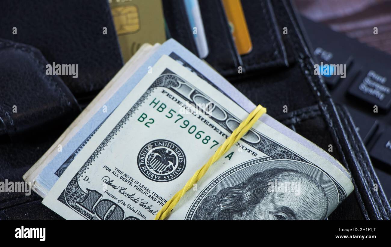 A stack of hundred-dollar bills is on the wallet in the form of a bribe ...