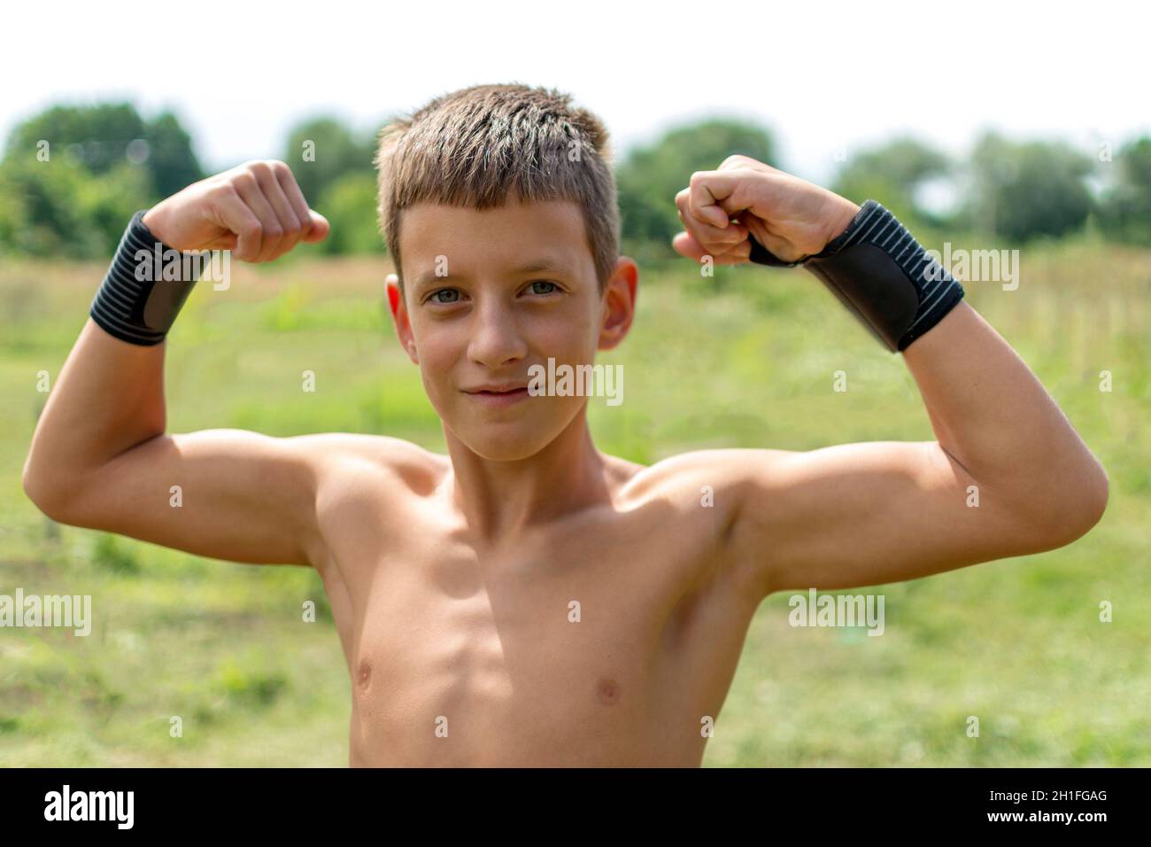 portrait of a boy in nature which shows his muscles Stock Photo - Alamy