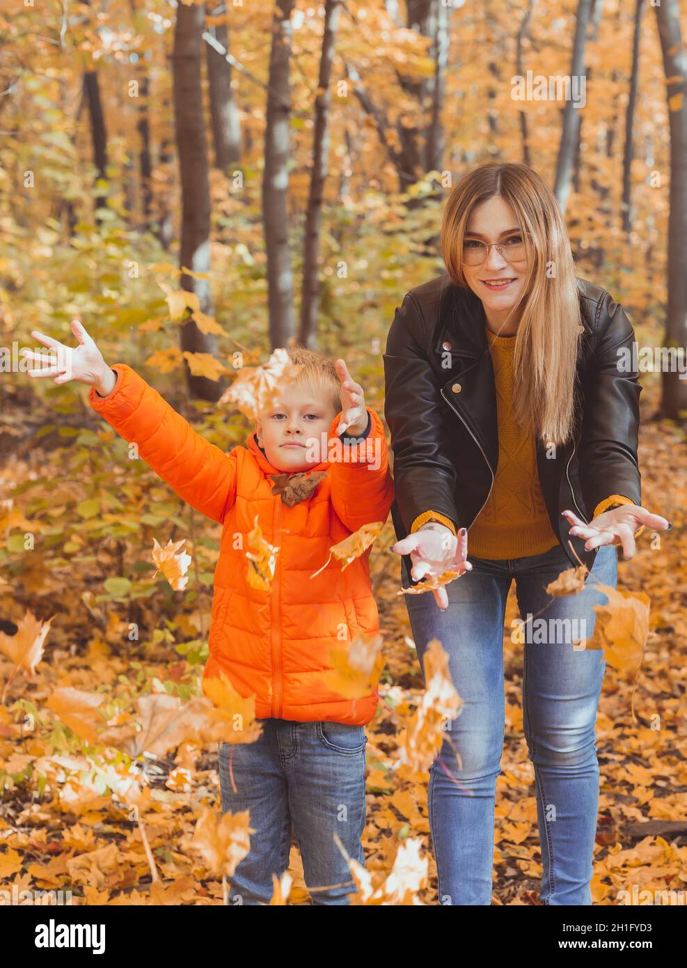 Single parent family playing with autumn leaves in park. Happy mom and ...