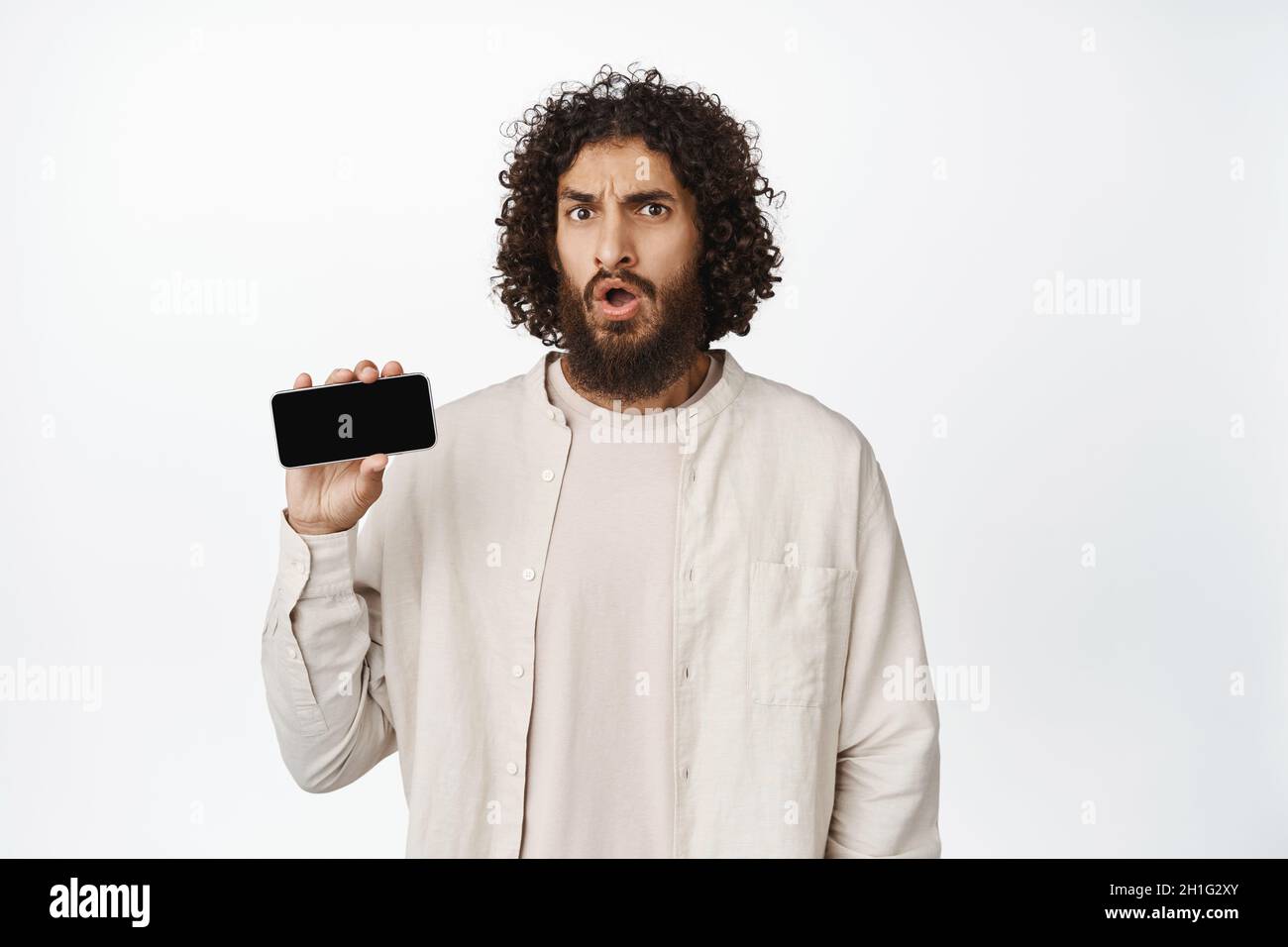 Shocked and confused middle eastern guy showing app interface ...