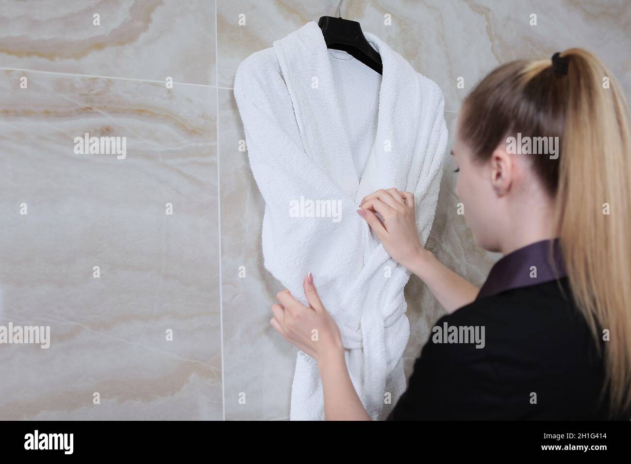 The cleaner adjusts her robe in the bathroom. Cleaning service at the ...