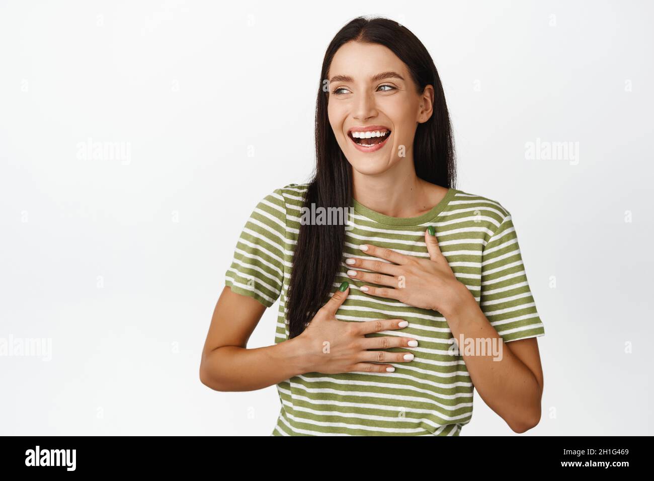 Candid happy woman laughing, holding hands on body and gazing aside ...