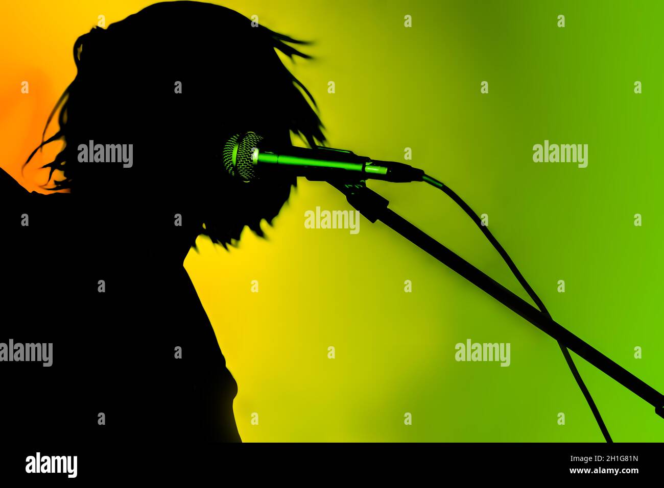 Silhouette of a male singer performing microphone in focus colorful ...