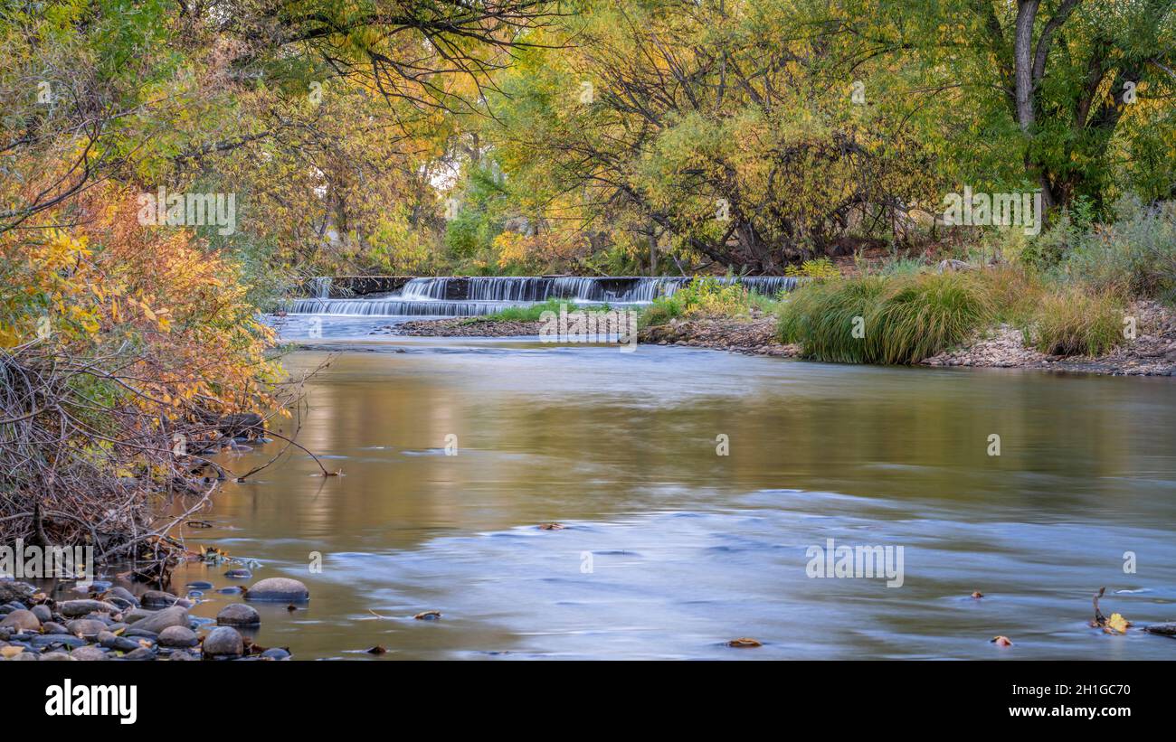 small river with a diversion dam in fall scenery - Cache la Poudre ...