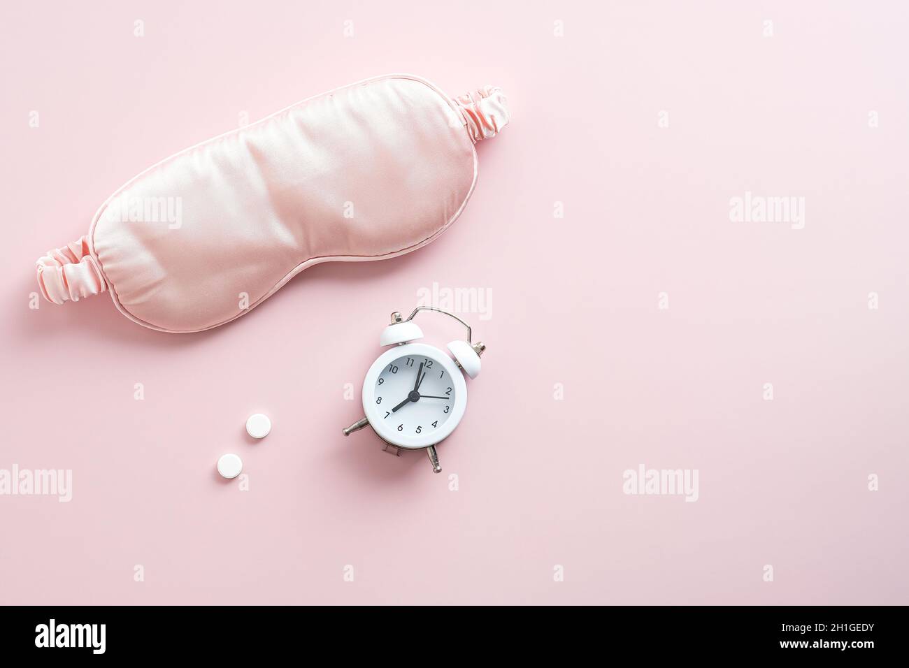 Sleeping eye mask, alarm clock, pills on pink background. Insomnia ...