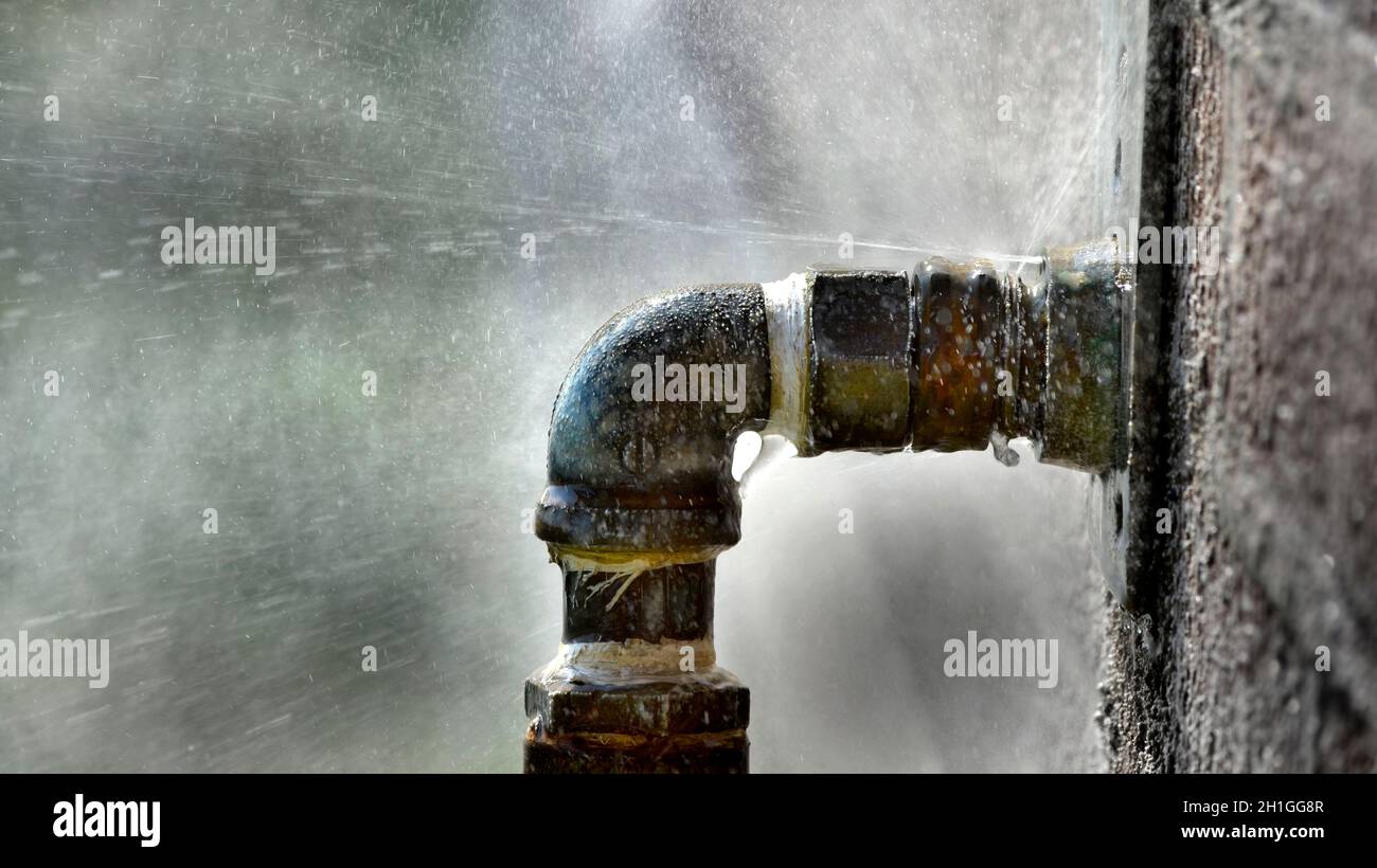 Old rusty pipe with leak and water spraying out under pressure leaky ...