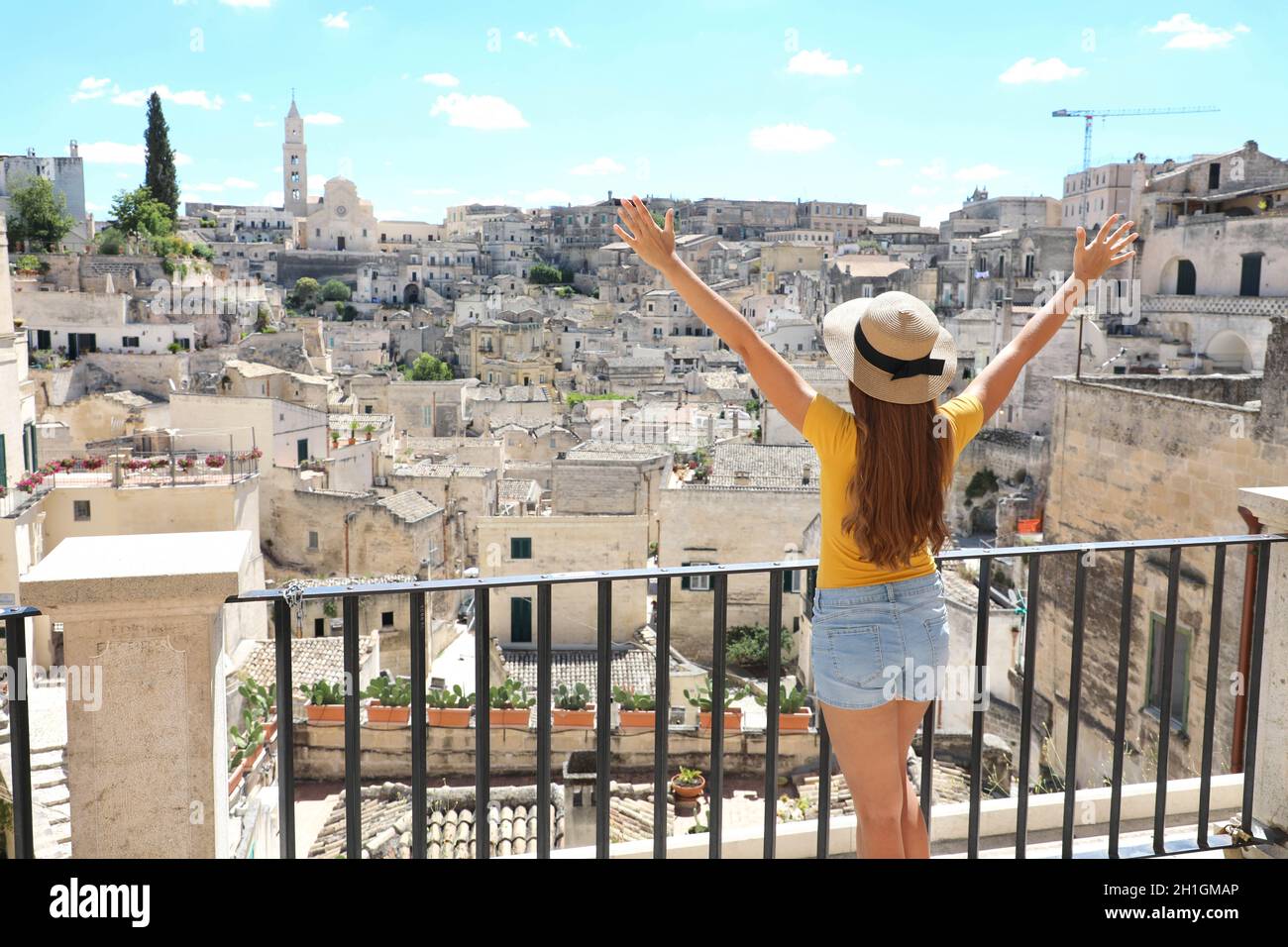 Happy tourist girl with arms raised up enjoys the stunning view of the ...