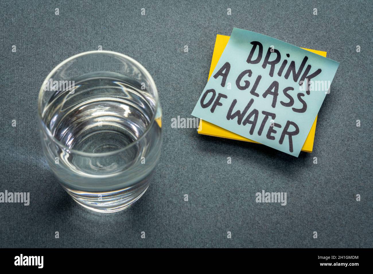 drink a glass of water - hydration reminder, handwriting on blue sticky ...