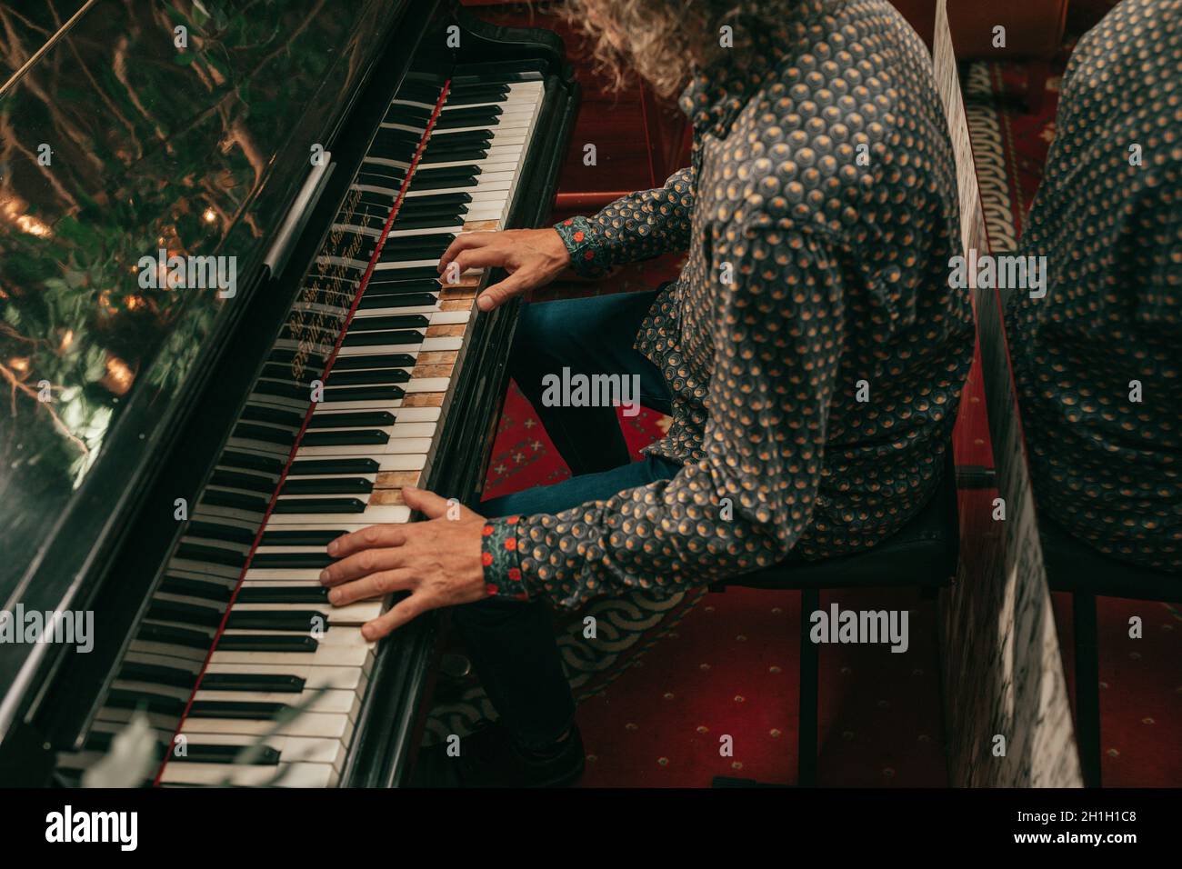 human hands of mature adult male person playing melody on keys of piano ...