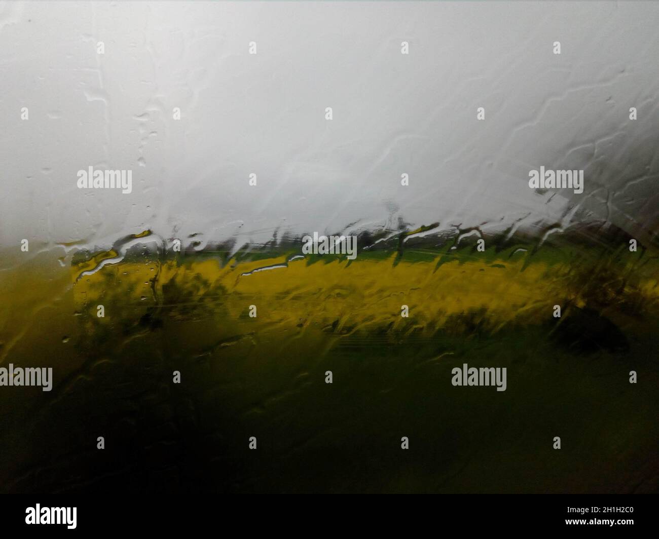 Wet window with a view of a road in a field Stock Photo - Alamy