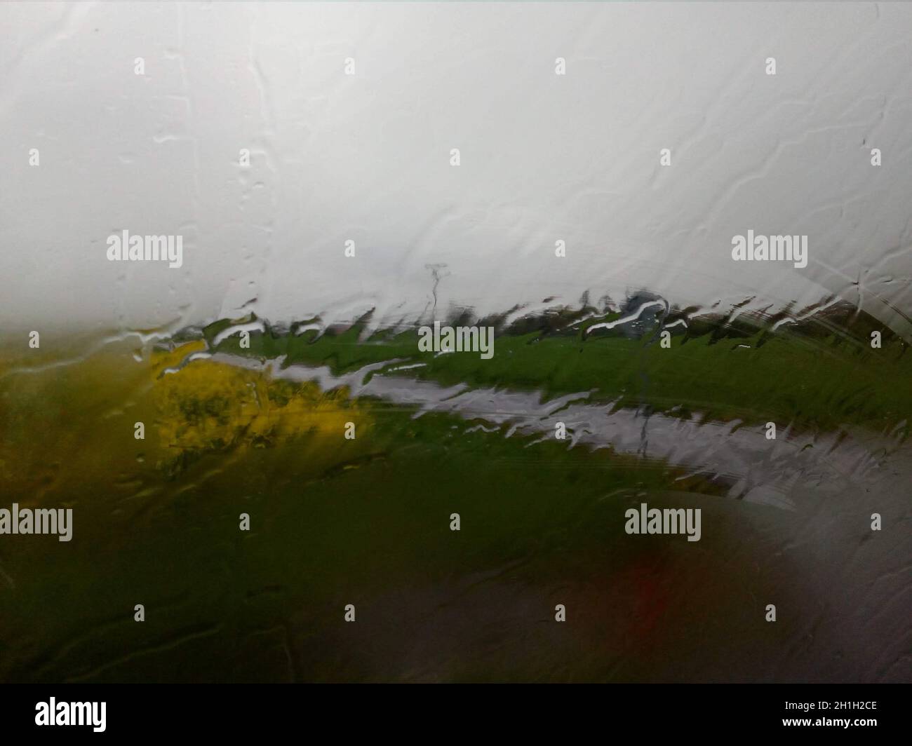 Wet window with a view of a road in a field Stock Photo - Alamy