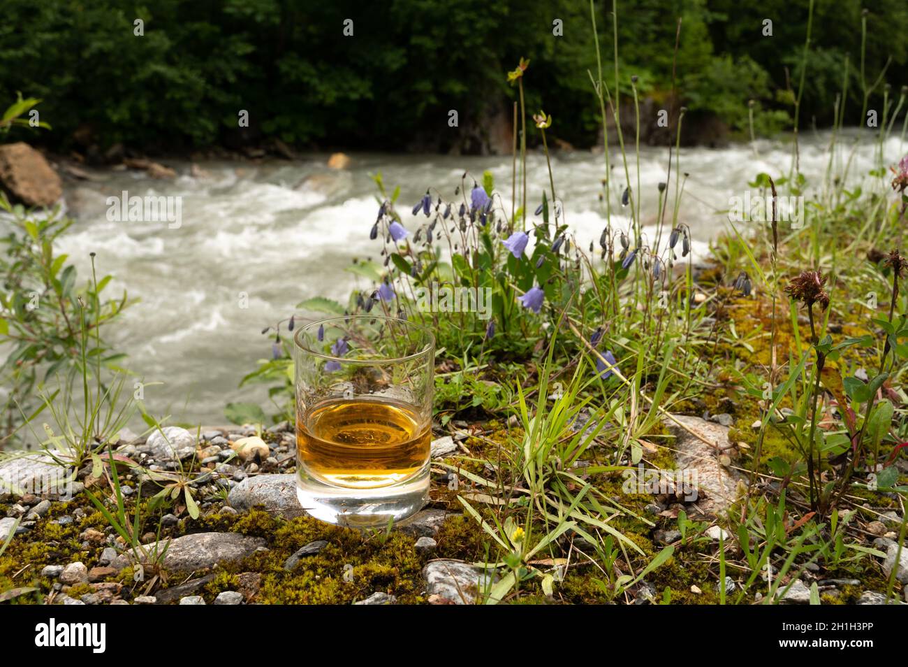 Glass of strong scotch single malt whisky with fast flowing mountain ...
