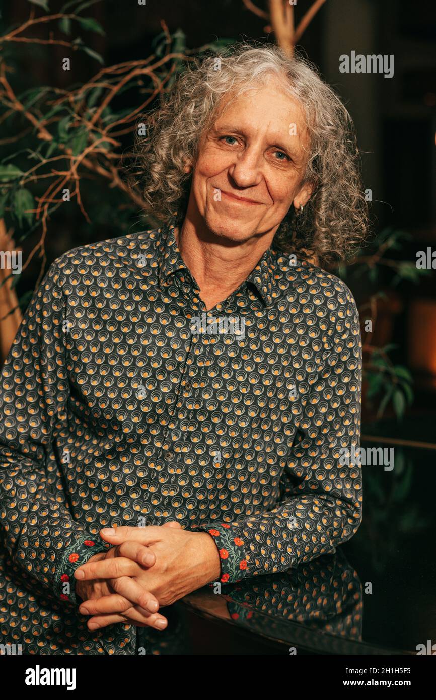 portrait of 65-year-old man with gray curly hair in t-shirt looks at ...