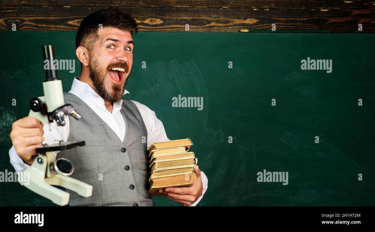 Happy teacher or student with books and microscope near blackboard with ...