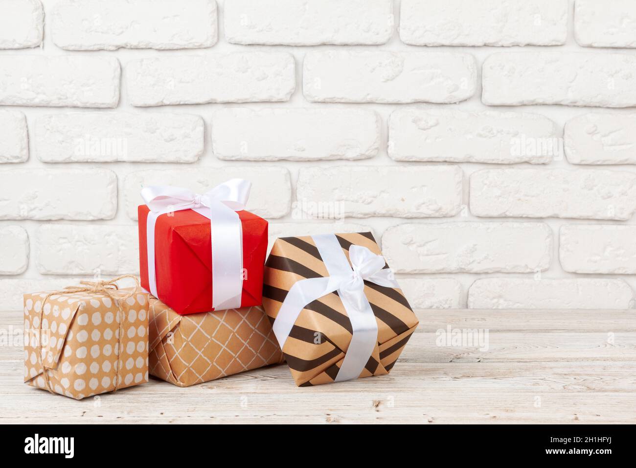 Colorful gift boxes against white brick wall background Stock Photo - Alamy
