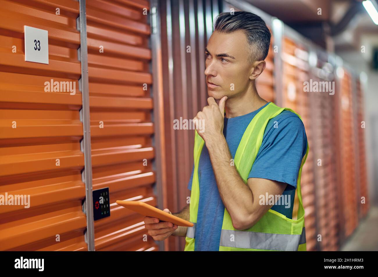 Thinking man with tablet looking at garage number Stock Photo - Alamy