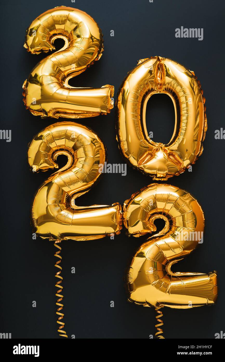 2022 year gold balloon on black background with golden ribbons. Happy ...