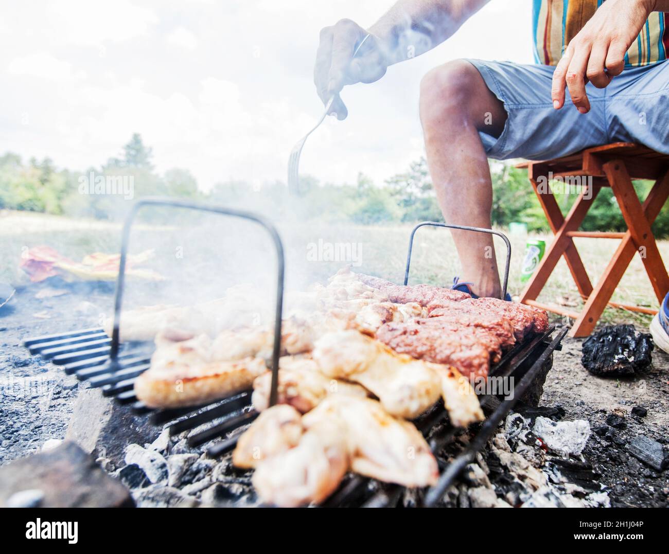 prepares a meat on the barbecue grill, unrecognizable man making ...
