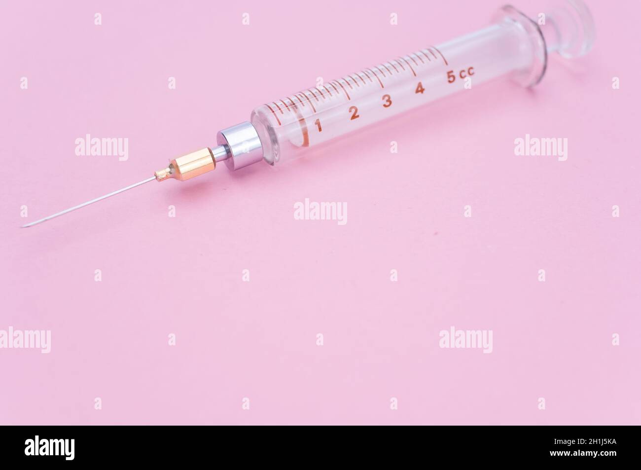 isolated sterilized glass injection syringe on a pink paper background ...