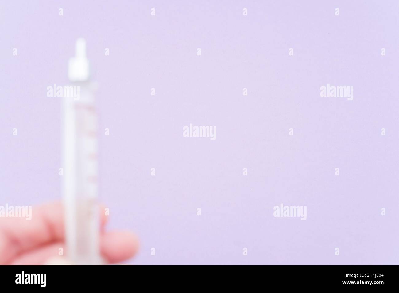 isolated sterilized glass injection syringe on a lilac paper background ...