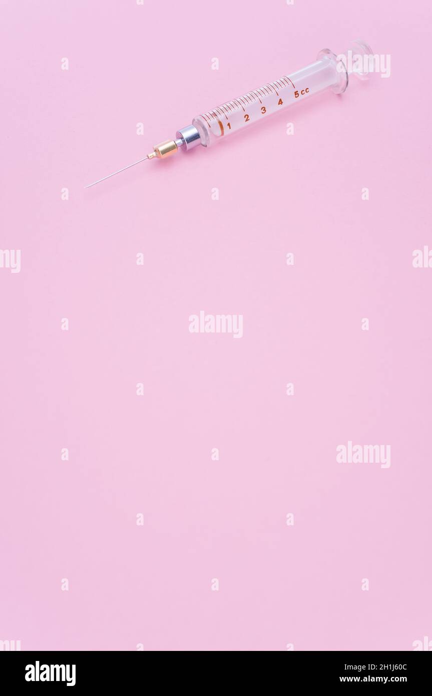 isolated sterilized glass injection syringe on a pink paper background ...