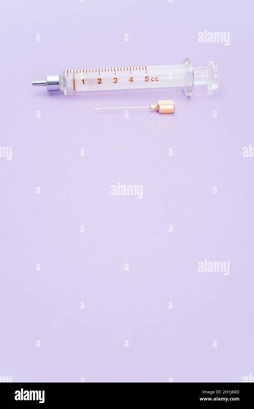 isolated sterilized glass injection syringe on a lilac paper background ...