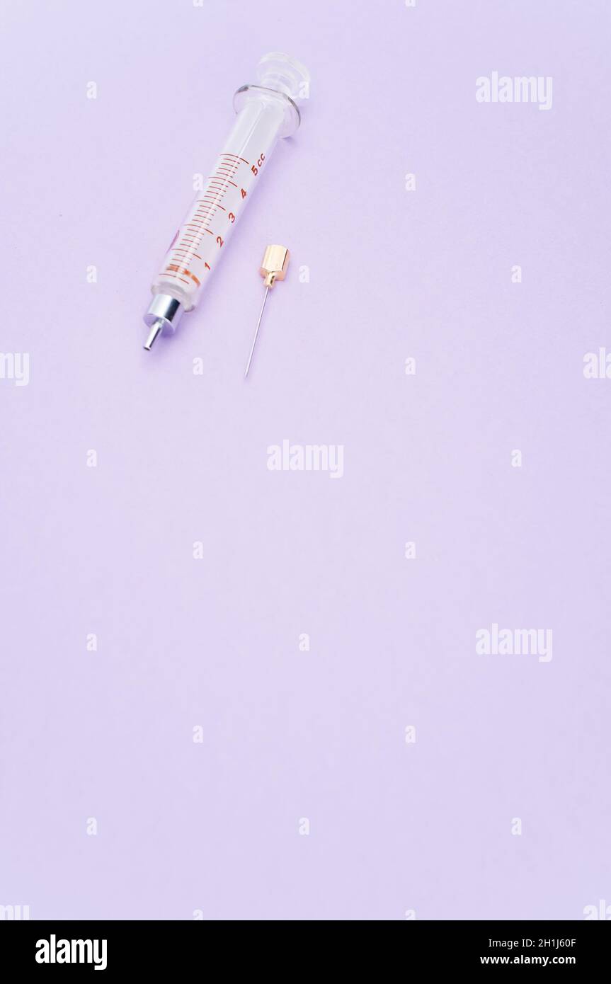 isolated sterilized glass injection syringe on a lilac paper background ...
