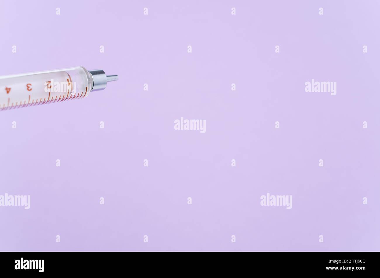 isolated sterilized glass injection syringe on a lilac paper background ...