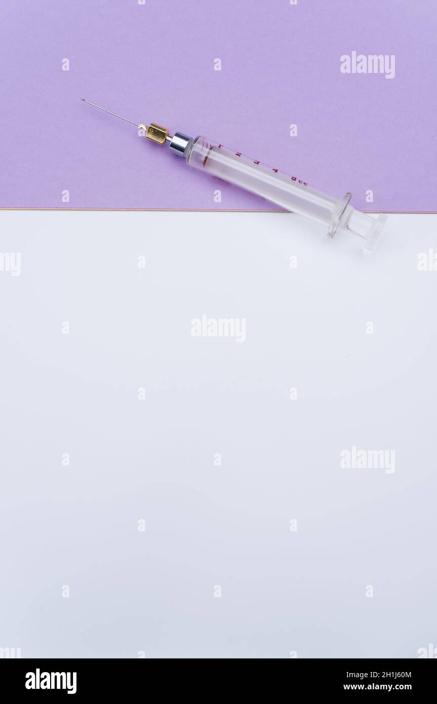 isolated sterilized glass injection syringe on a lilac paper background ...