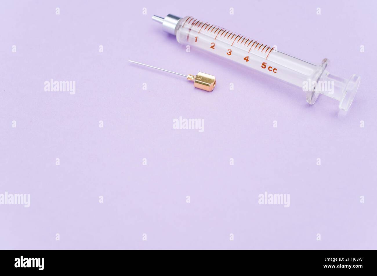 isolated sterilized glass injection syringe on a lilac paper background ...