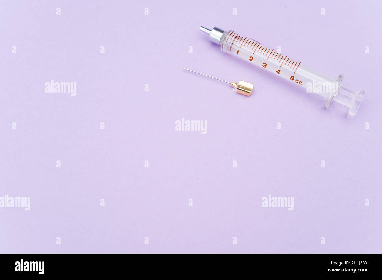 isolated sterilized glass injection syringe on a lilac paper background ...