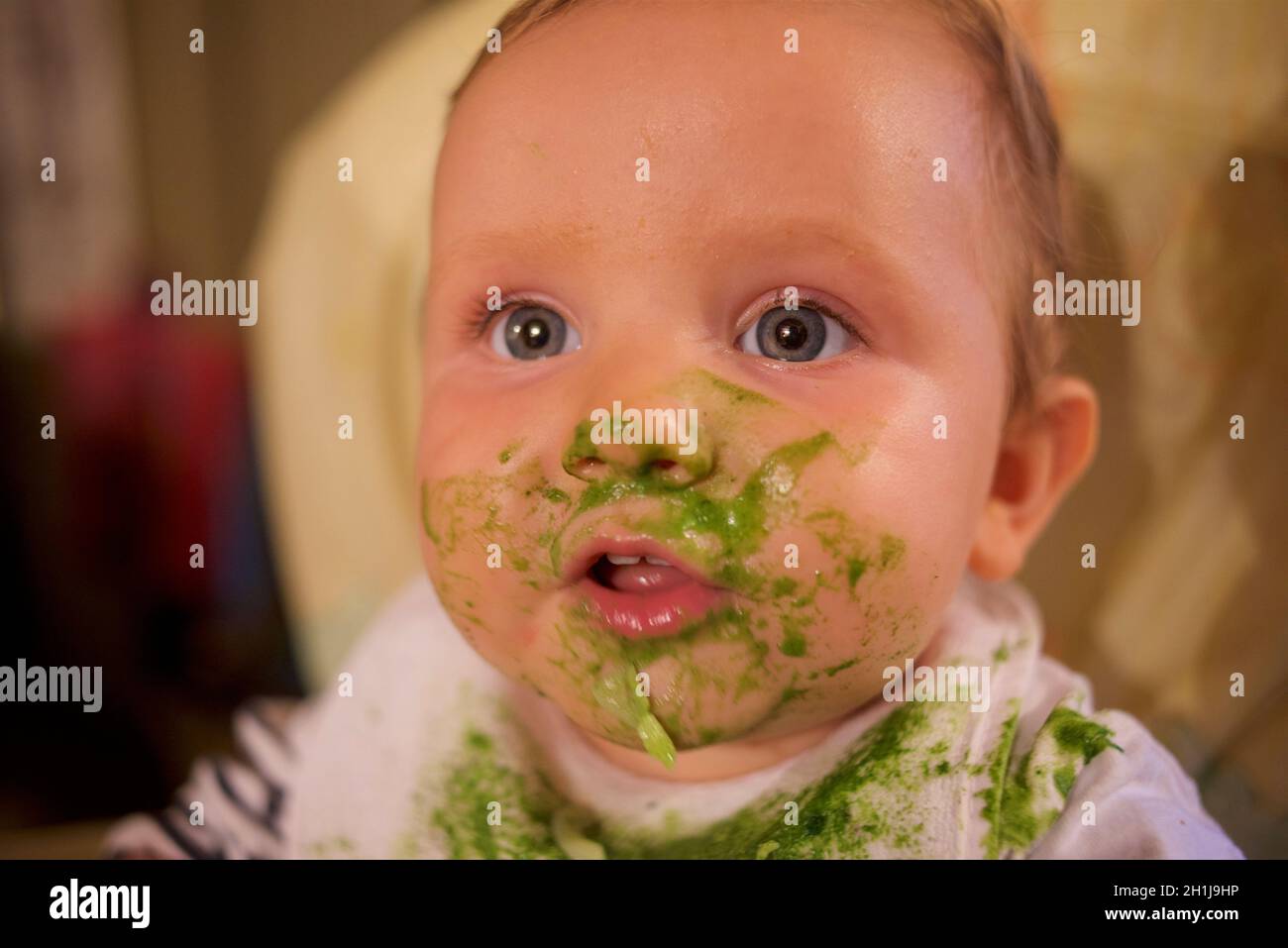 Baby face, smotthered in green food. Happy eater, messy eater. Model ...