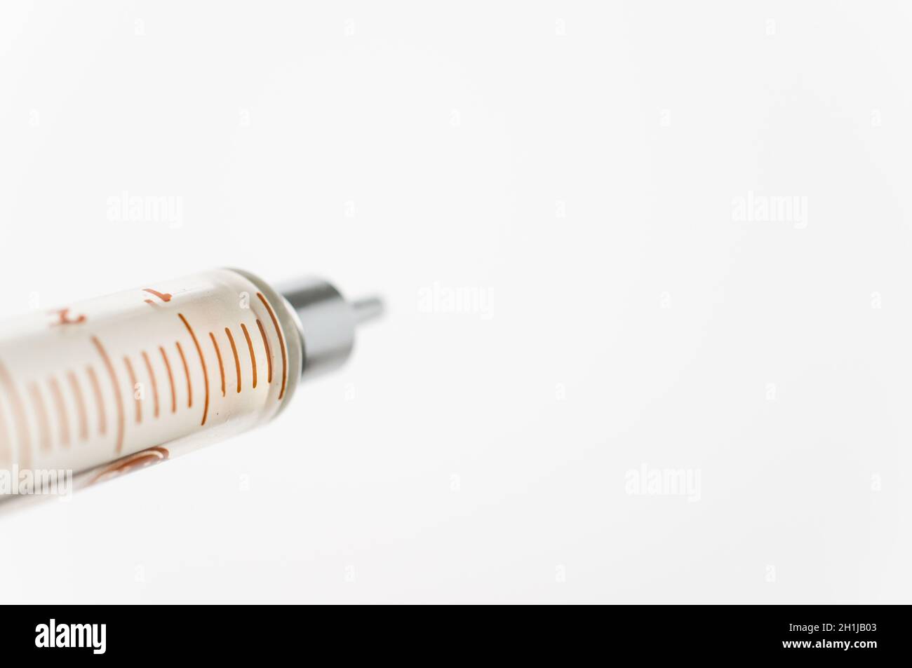 isolated sterilized glass injection syringe on a white paper background ...