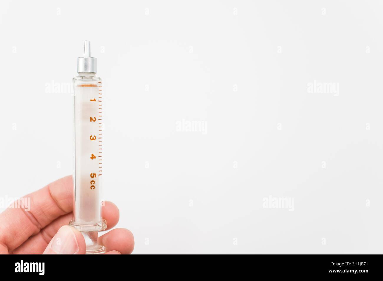 isolated sterilized glass injection syringe on a white paper background ...