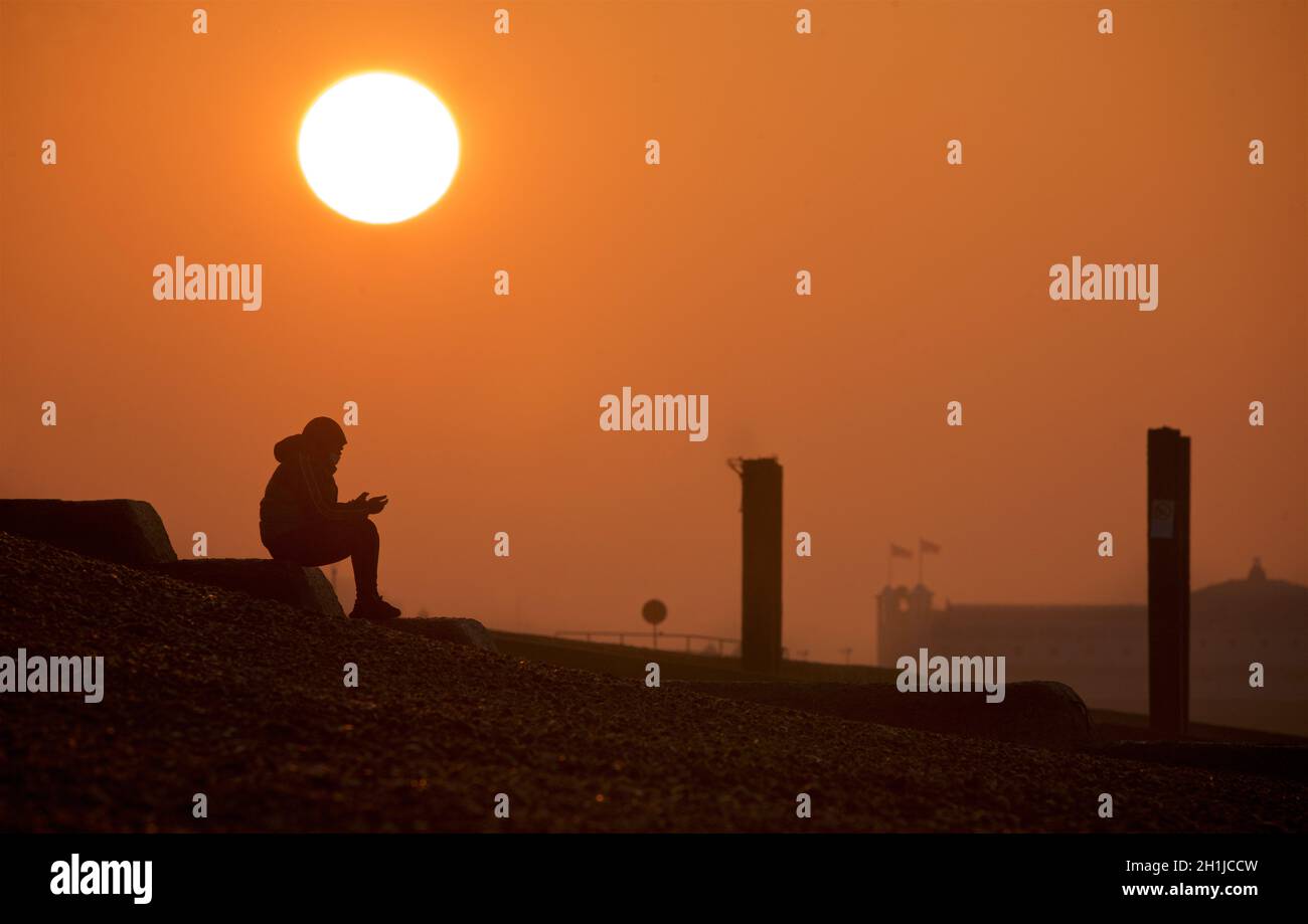 Early morning, Brighton beach. Sunrise. Silhouetted shape of man ...