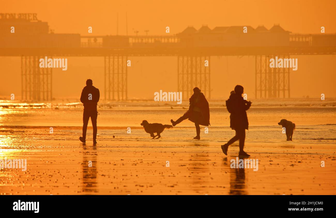 Brighton beach at low tide, sunrise. The Palace Pier silhouetted in the ...