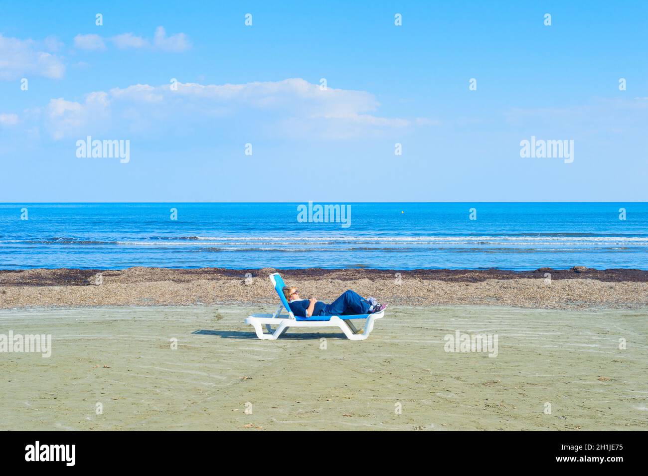 LARNACA, CYPRUS - FEB 18, 2019: Woman taking sunbathes on a deserted ...