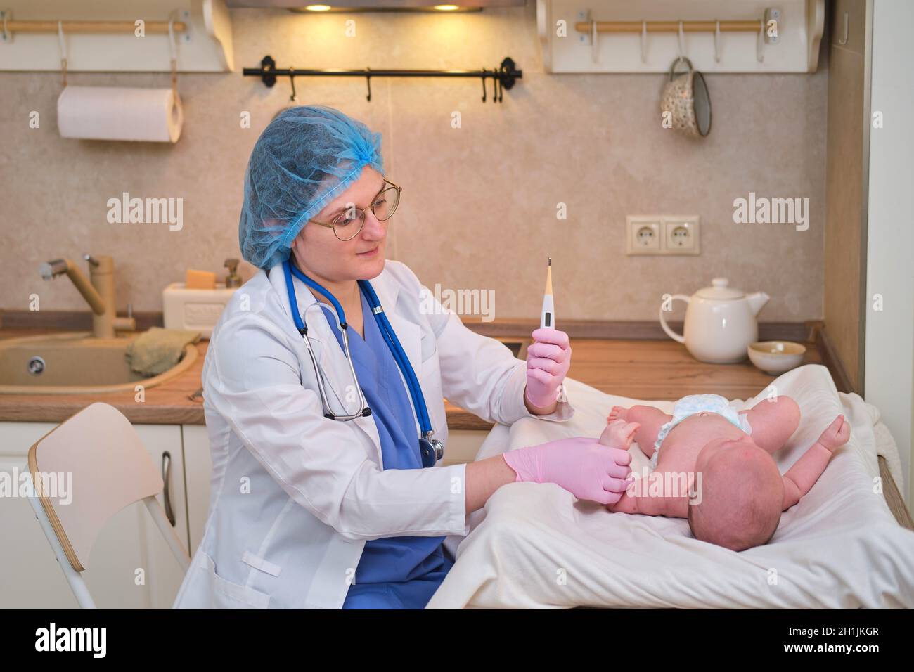 Doctor checks the temperature of the newborn baby with a thermometer. A ...