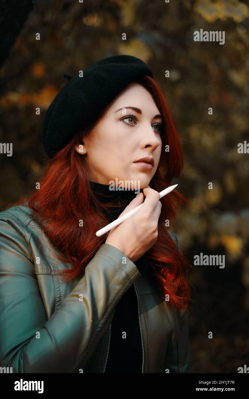 Beautiful red-haired woman in the park. Brooding woman in a beret and ...