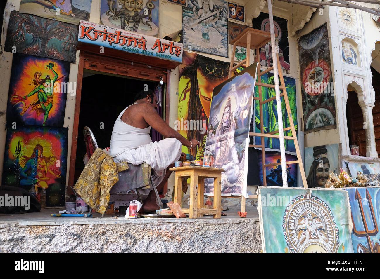 Local artist painting canvas pictures which are sold to tourists ...