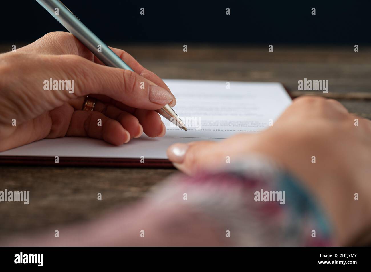 Low angle view of female hand signing a document, application form or ...