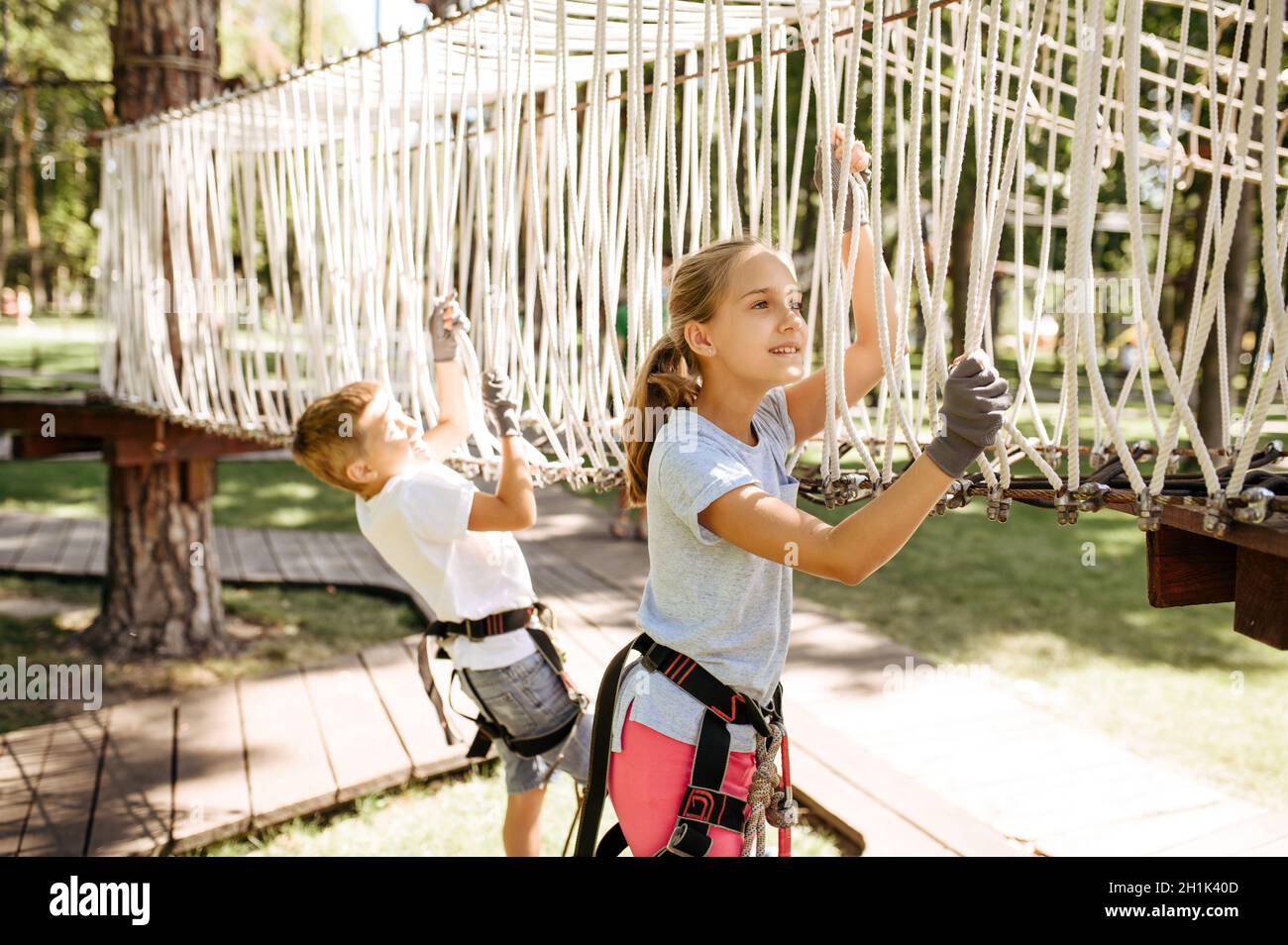 Little brave kids climbs on net in rope park, playground. Children ...